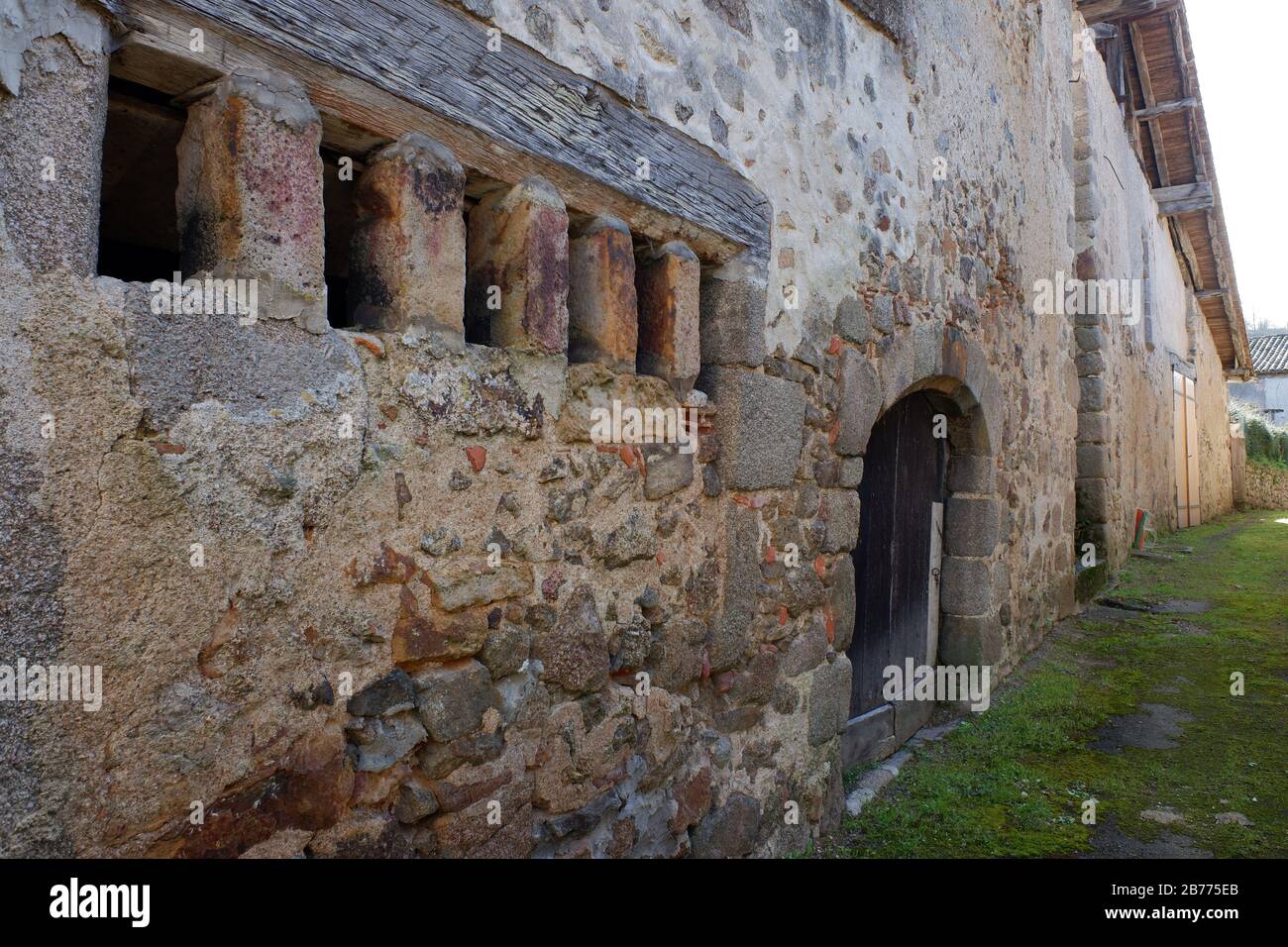 Shot of the white stone wall with wooden windows Stock Photo - Alamy