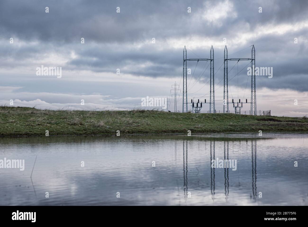 Low angle shot of a transmission line with a cloudy sky reflected on ...