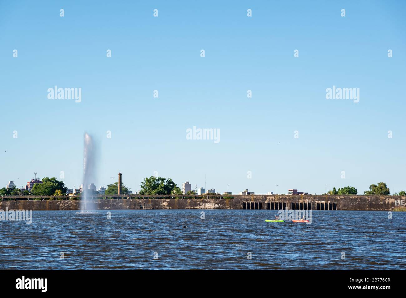 A big blue lake with people with their kayaks and a spring of water ...