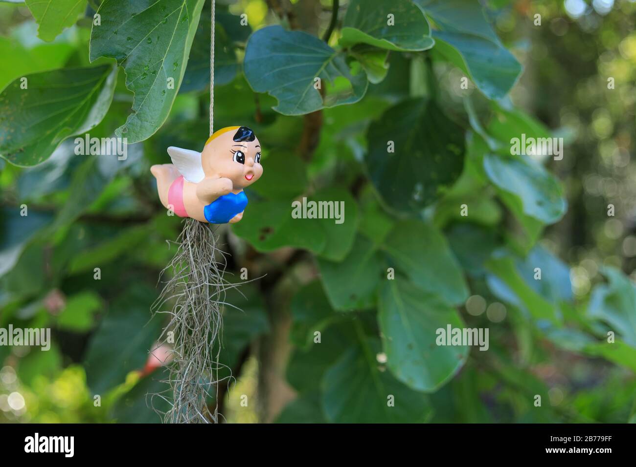 Clay doll hanging with green tree background Stock Photo - Alamy
