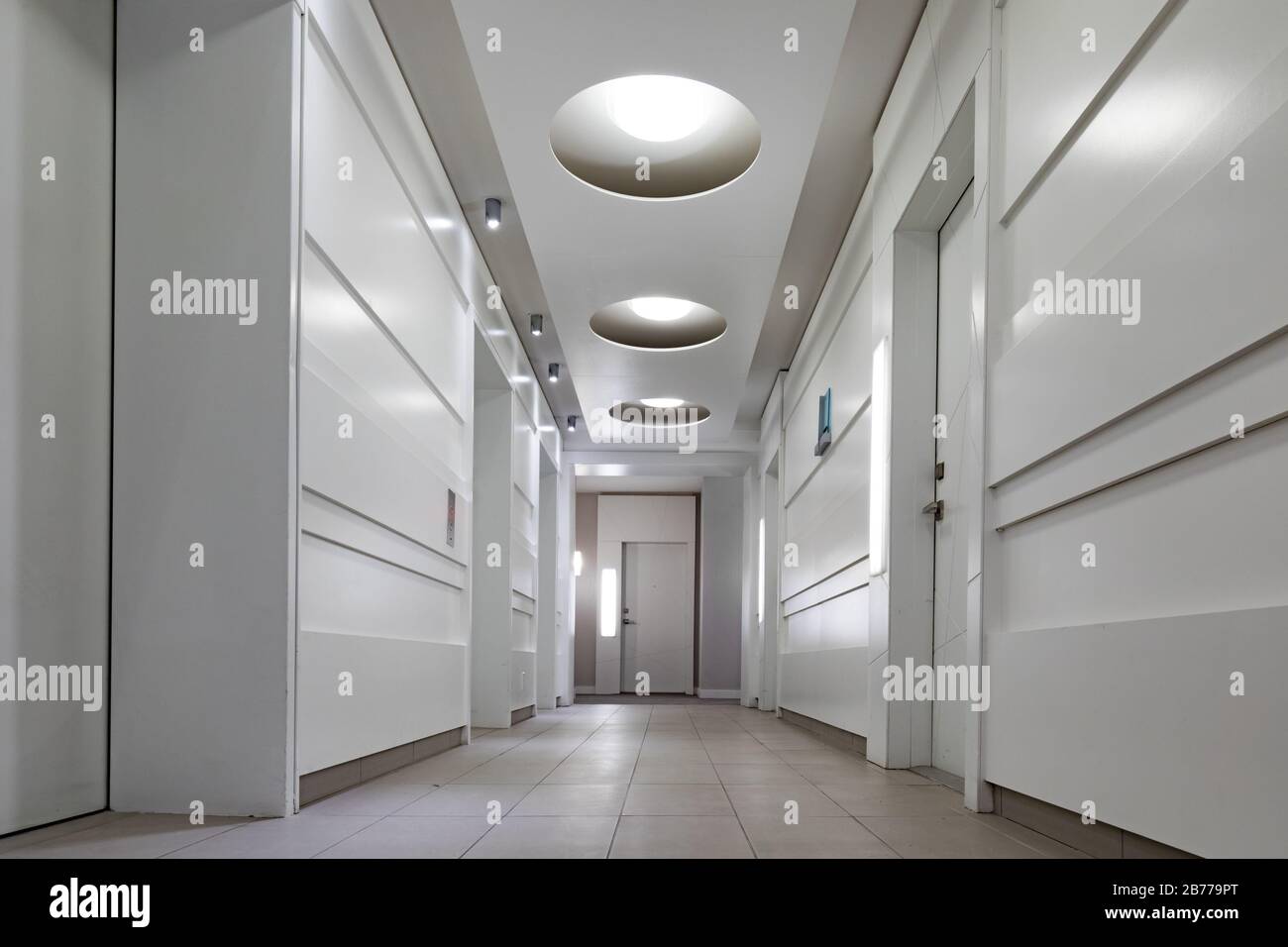 White hall inside a building with turned-on lights hanging on the ...