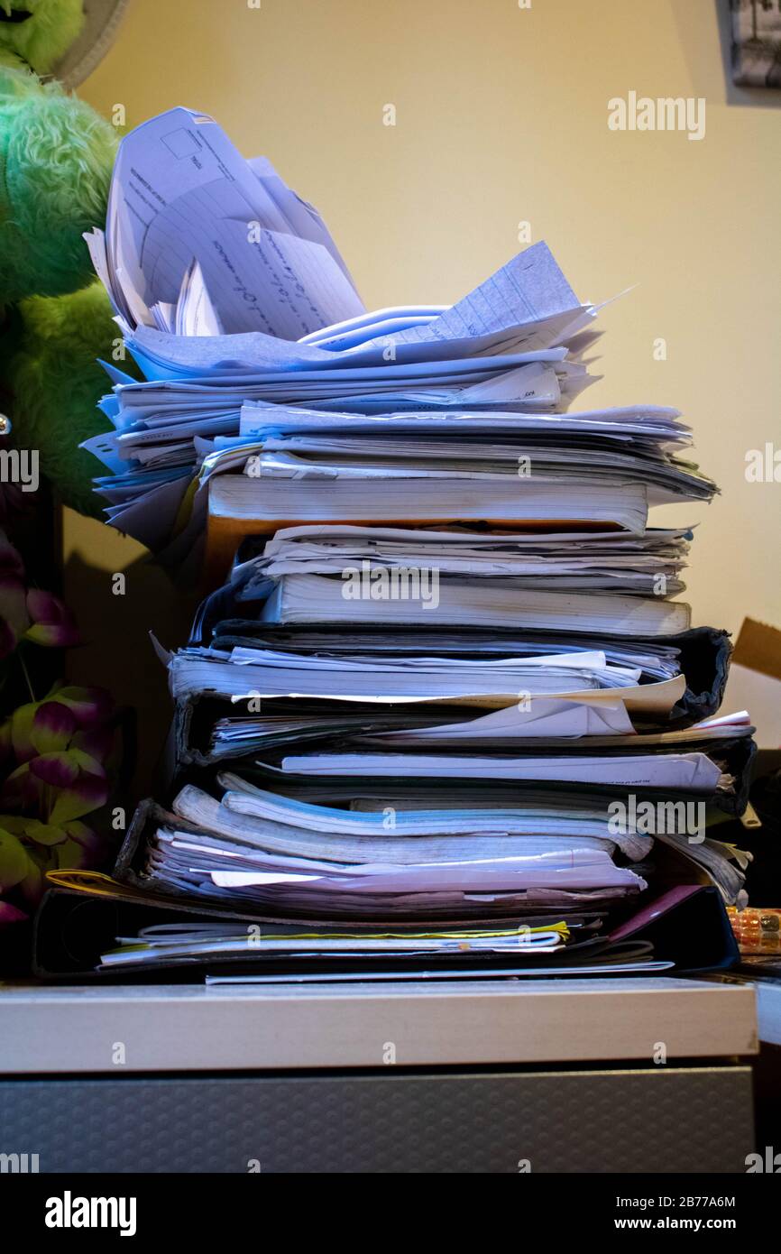 Vertical picture of papers and folders on top of each other on a table ...