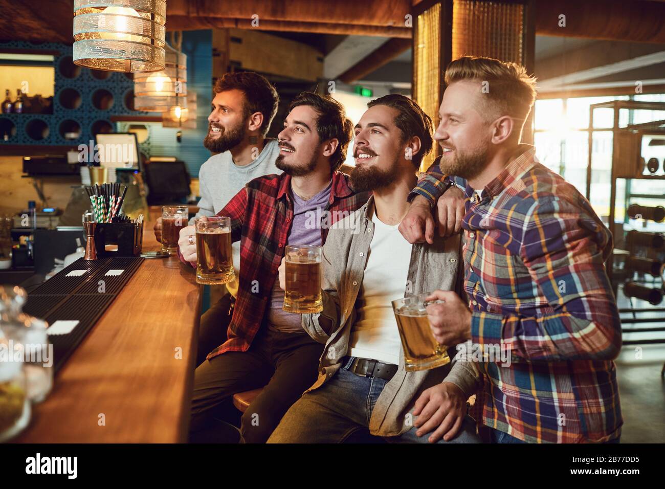 A group of guys watching sports on tv in a pub bar Stock Photo - Alamy