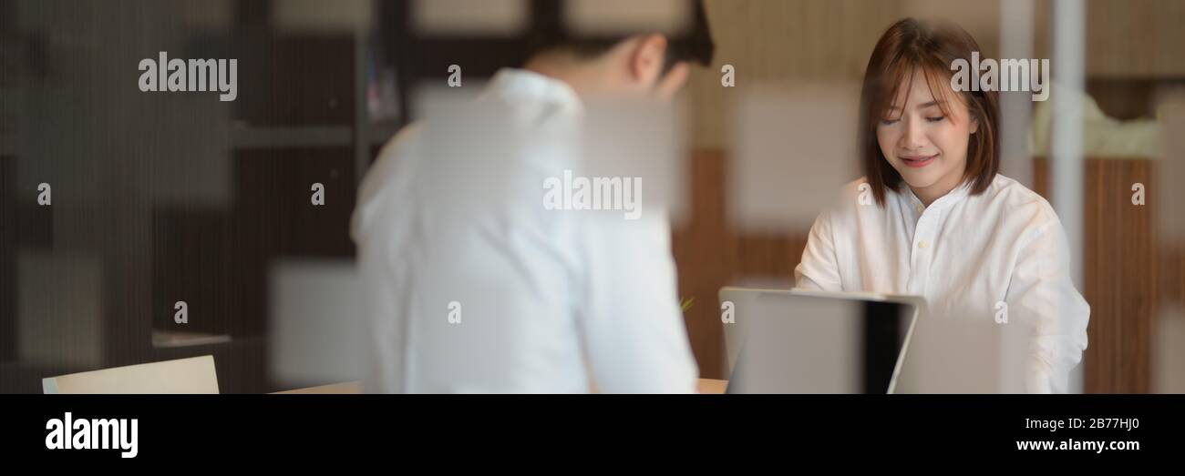 View through glass window of happy businesswoman focusing on her work ...