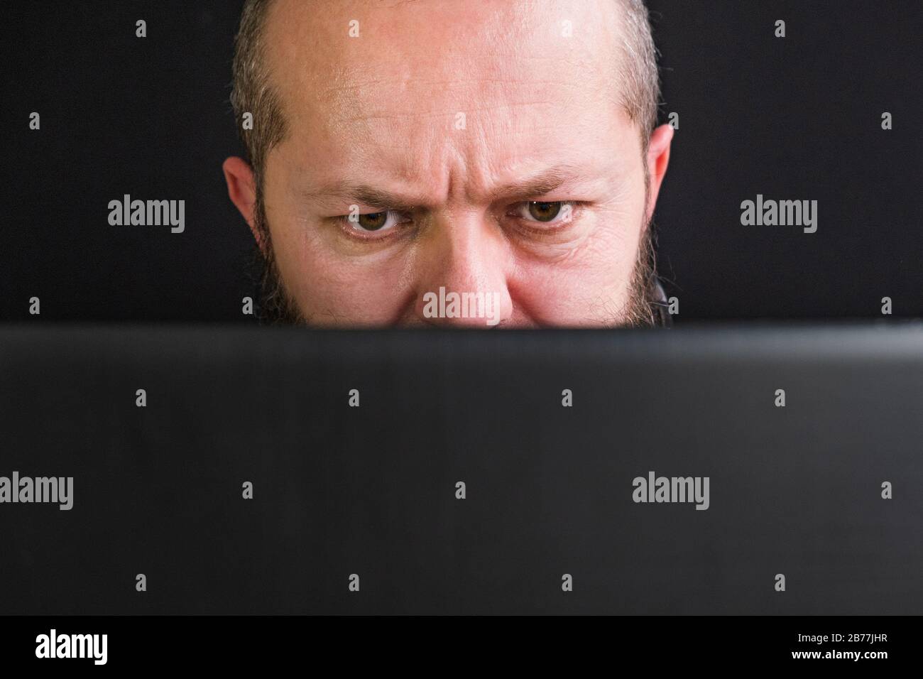Close up portrait of caucasian adult man sitting behind the laptop and ...