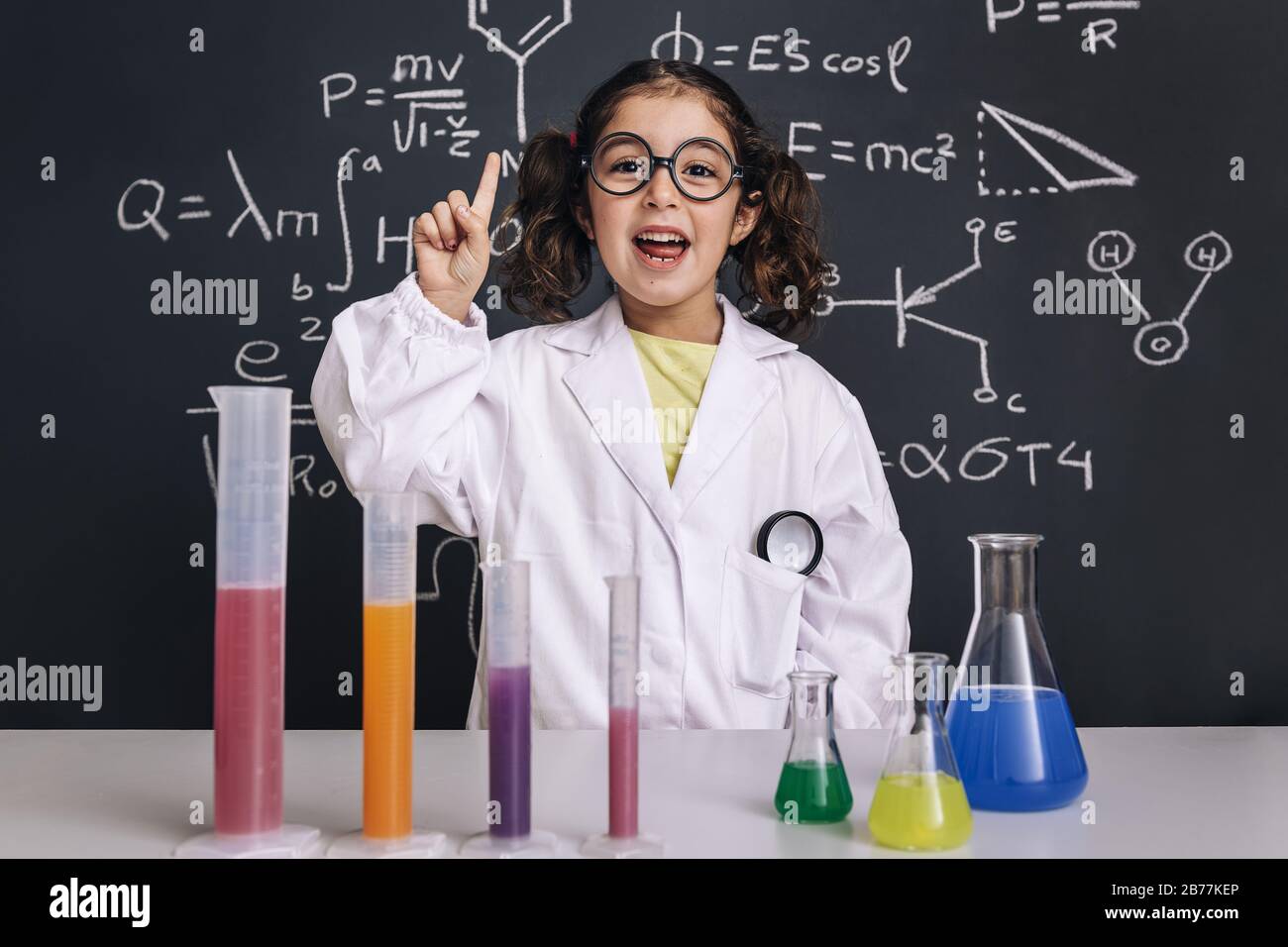 little scientist girl with glasses in lab coat with chemical flasks ...