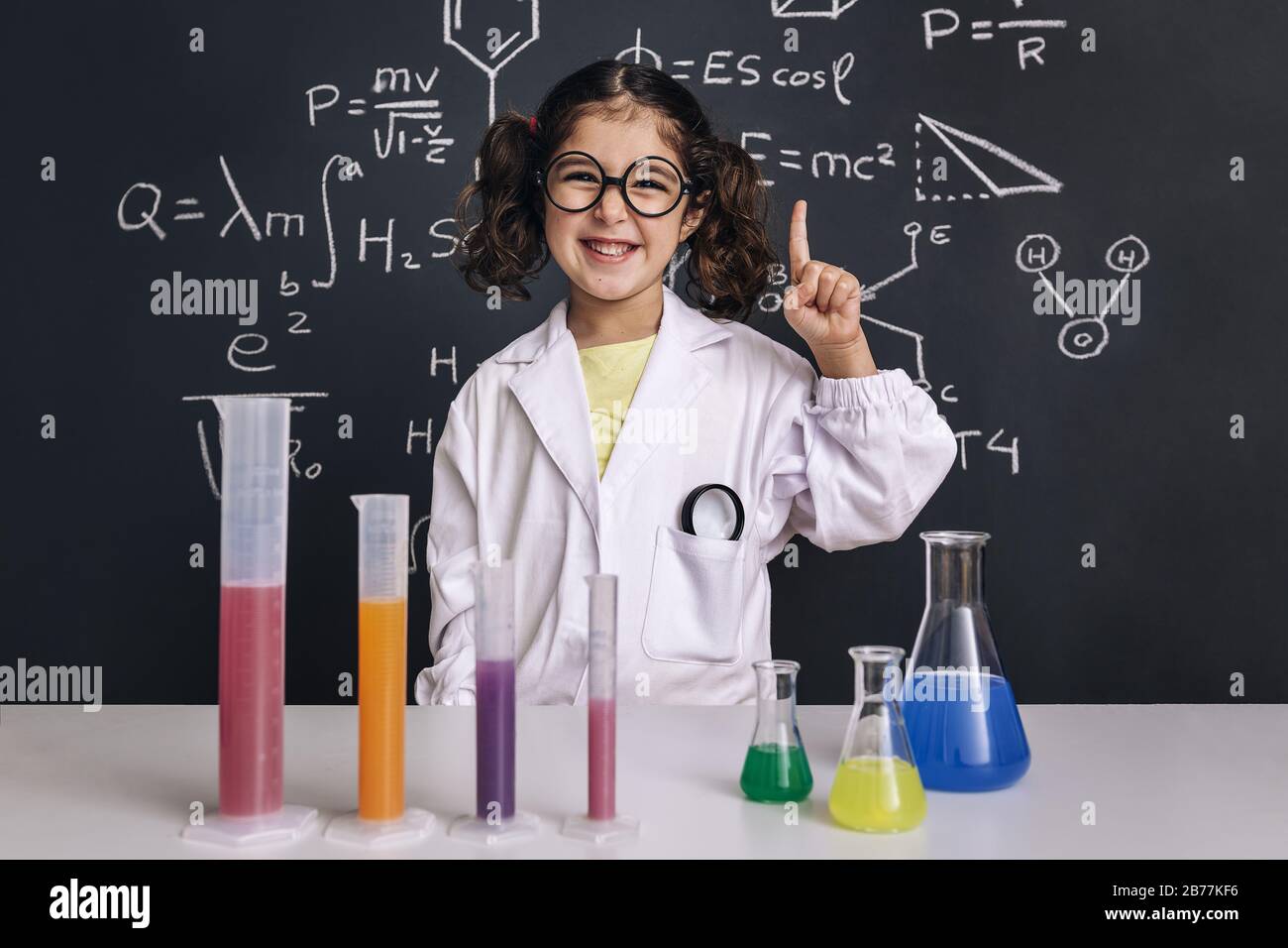 smiling scientist child with glasses in lab coat with chemical flasks ...
