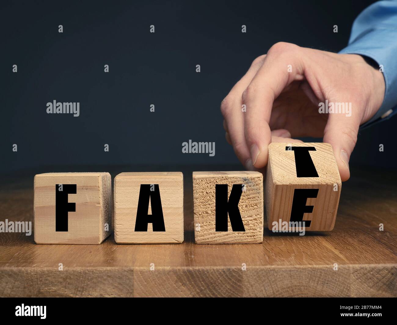 German fake or fact concept with businessman hand turning wooden blocks ...