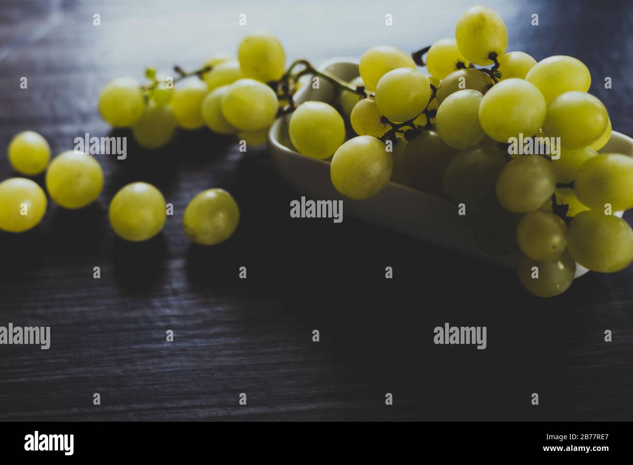 Spilled white grapes on wooden table Stock Photo - Alamy