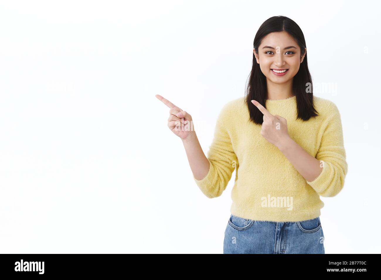 Beautiful happy smiling asian girl introduce product promo, pointing ...