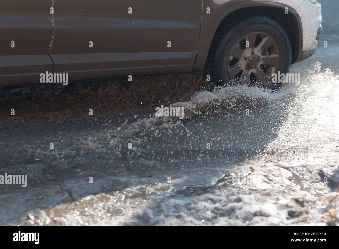 Vehicle car rides through spring puddles from melted snow. Spray from ...