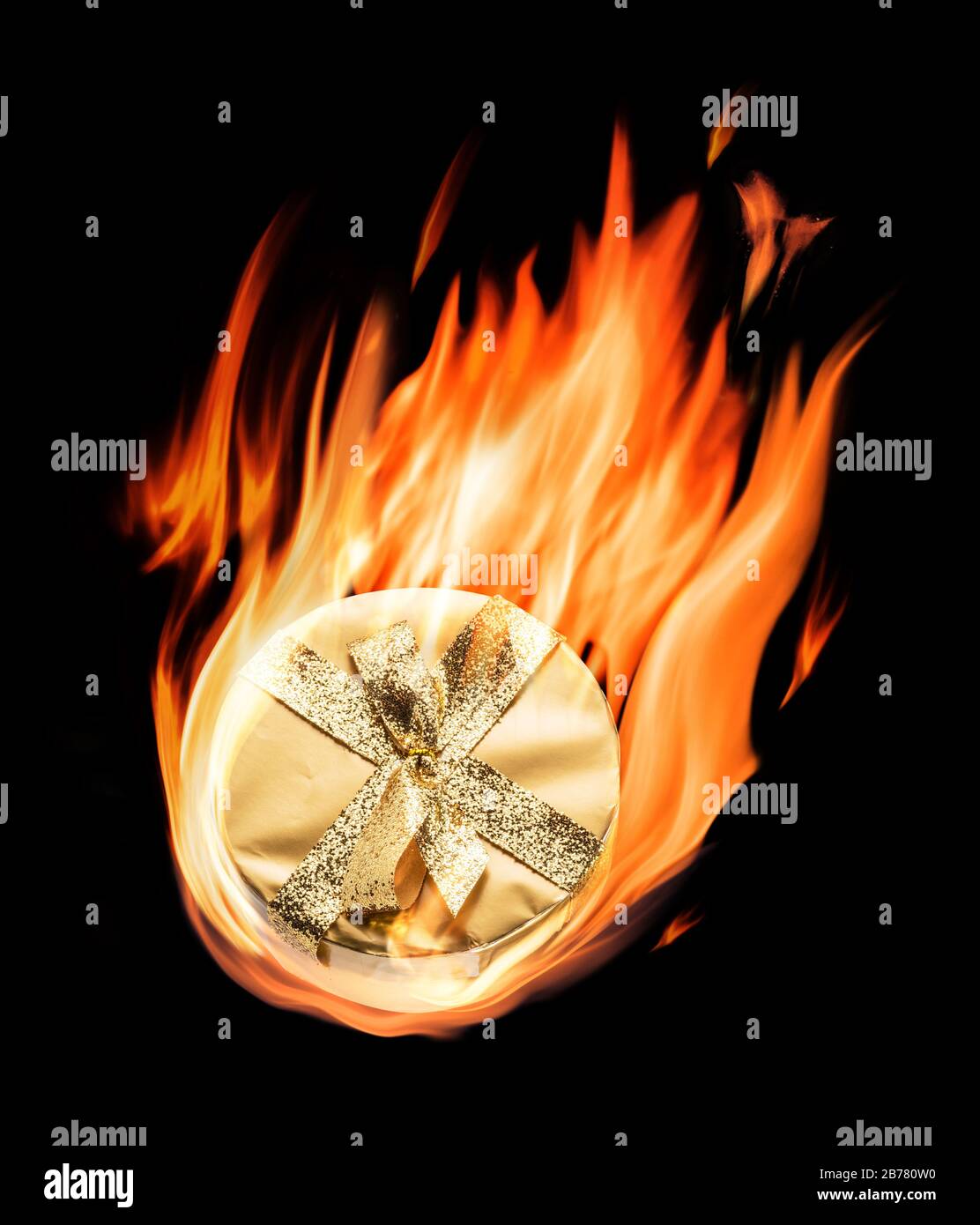 Burning gift box packed in golden paper on black background Stock Photo ...
