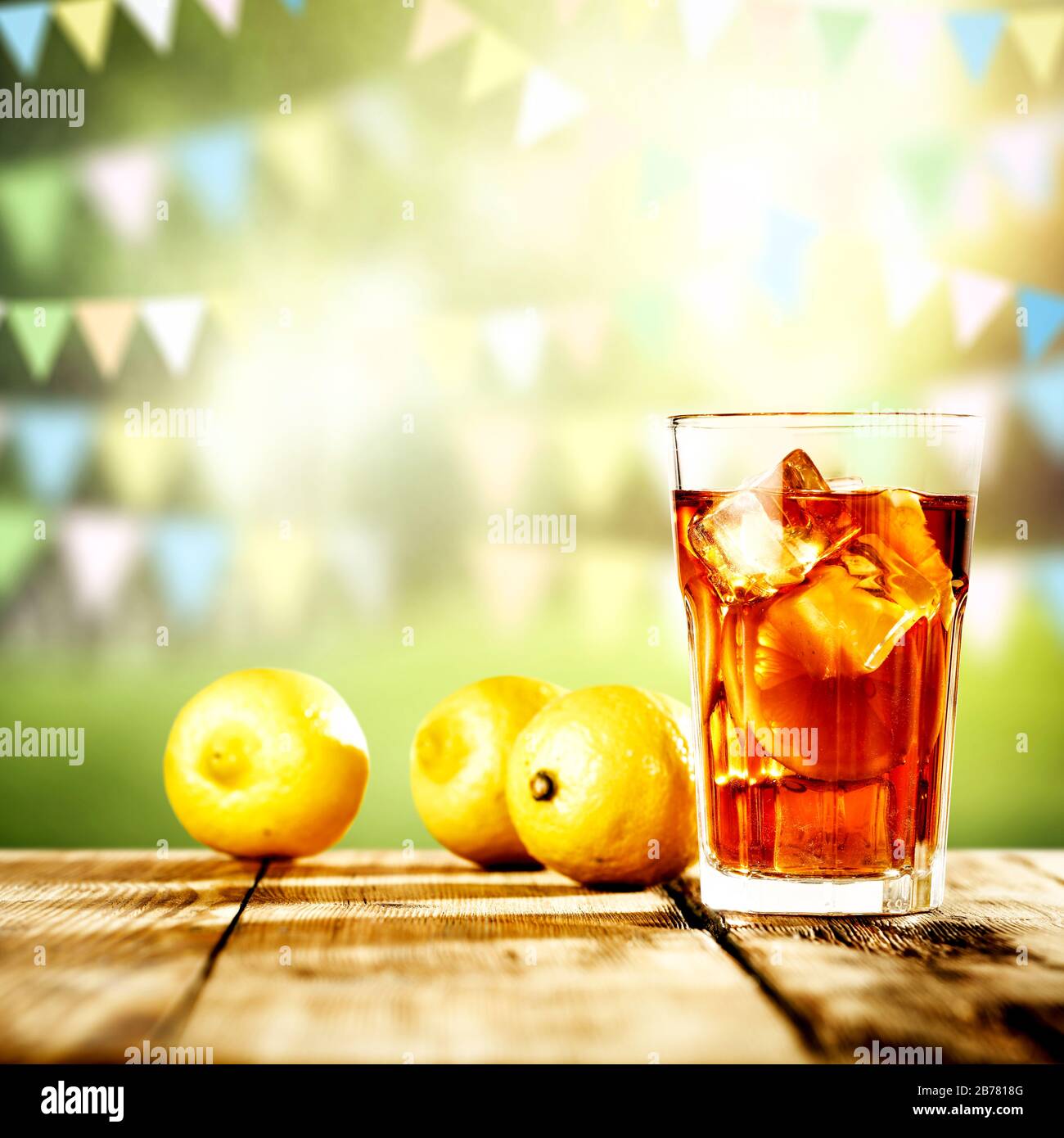 Ice tea in a big glass on wooden table with blurred spring outdoor ...