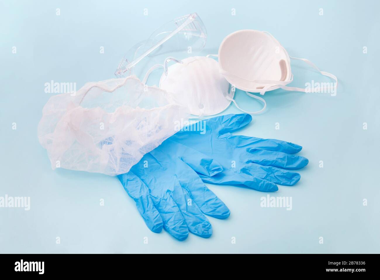 dust mask, blue gloves and head cover isolated on a light blue ...