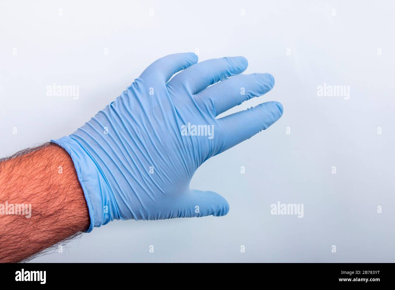 Doctor's hand in a blue medical glove over a light blue background ...