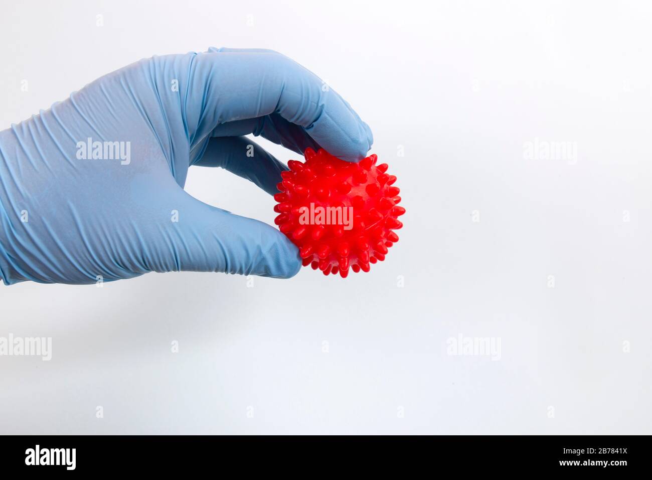 Doctor's hand holding red virus ball concept over a light blue ...