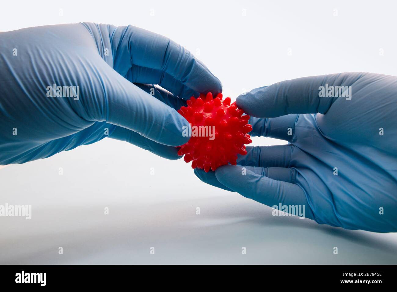 Doctor's hand holding red virus ball concept over a light blue ...