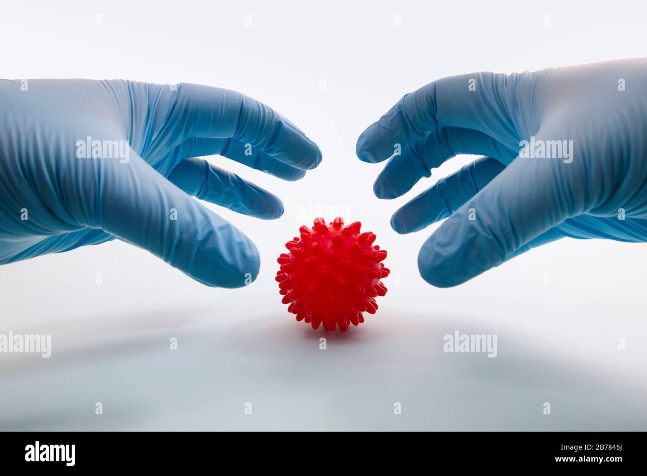 Doctor's hand holding red virus ball concept over a light blue ...