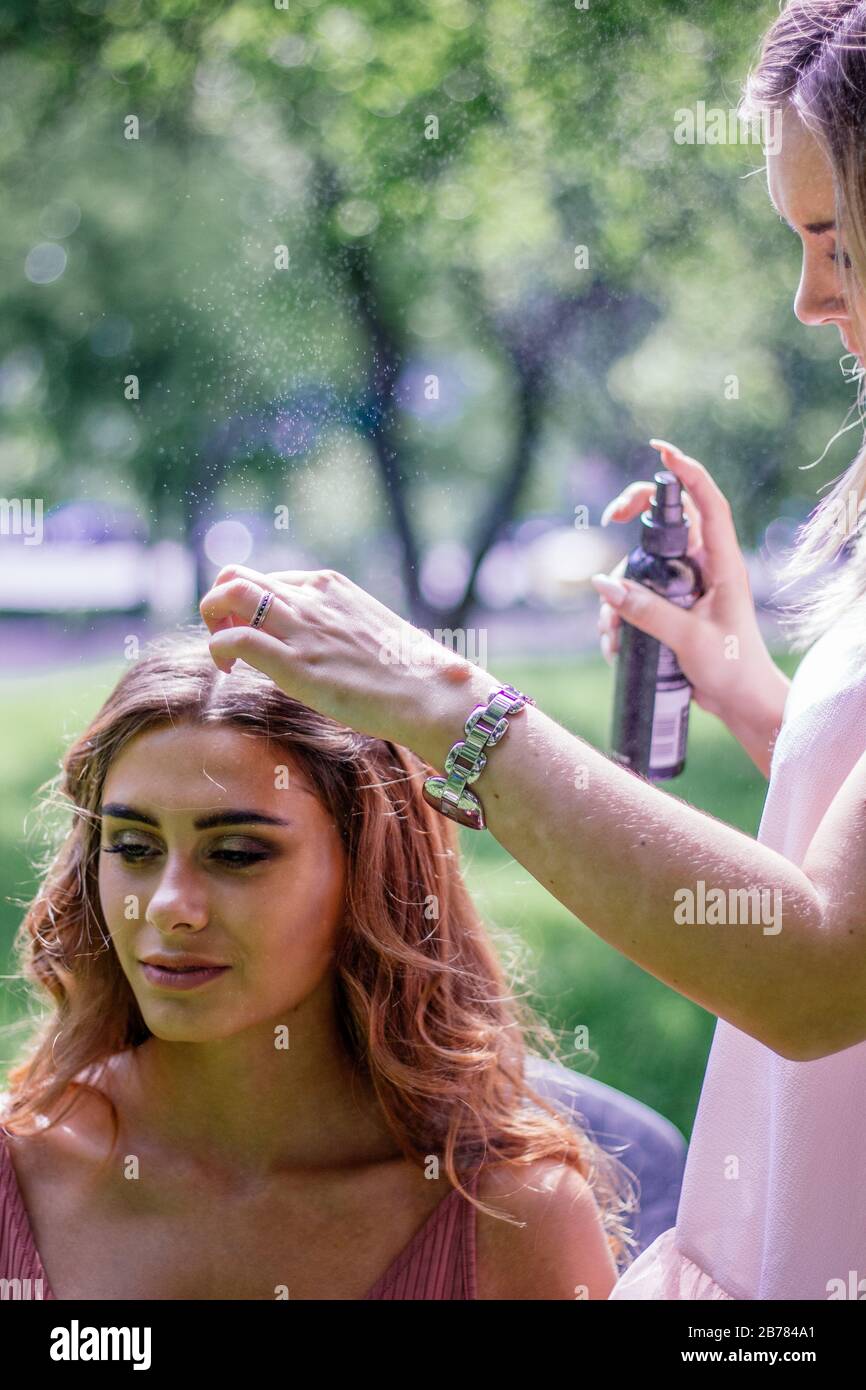 Stylist spraying hairs of young girl with hair spray Stock Photo - Alamy
