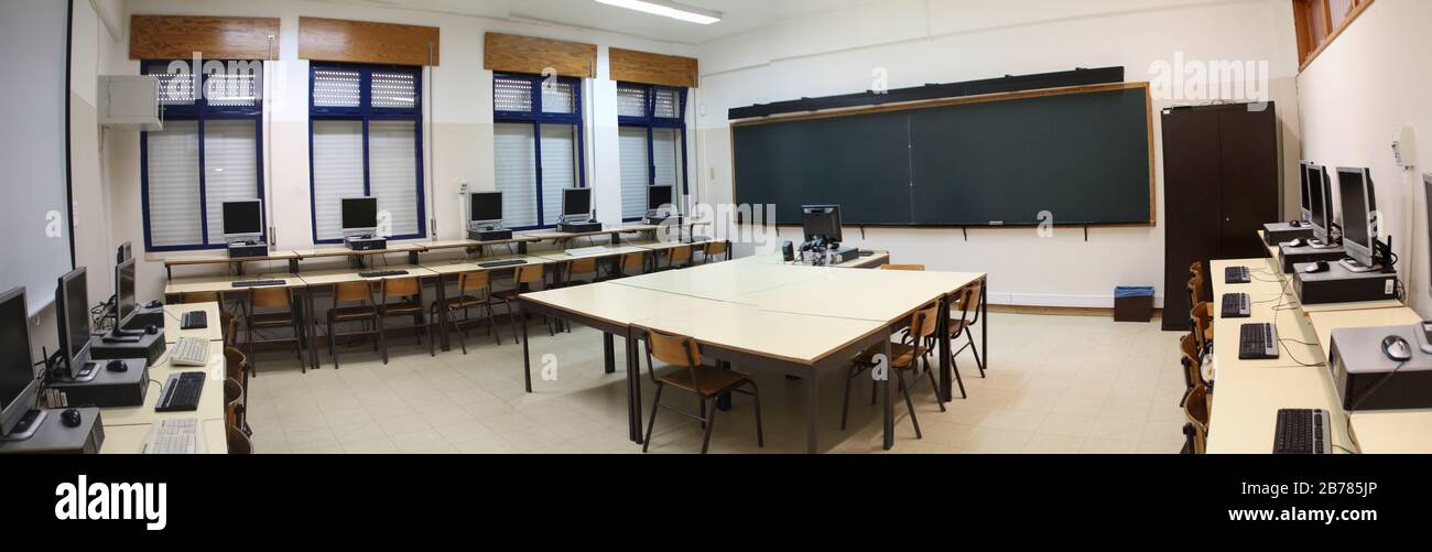View of the interior of a classroom with row of computers on middle ...
