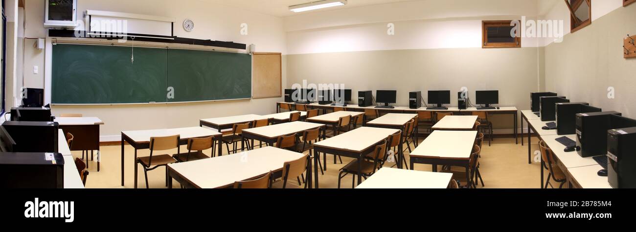 View of the interior of a classroom with row of computers on middle ...