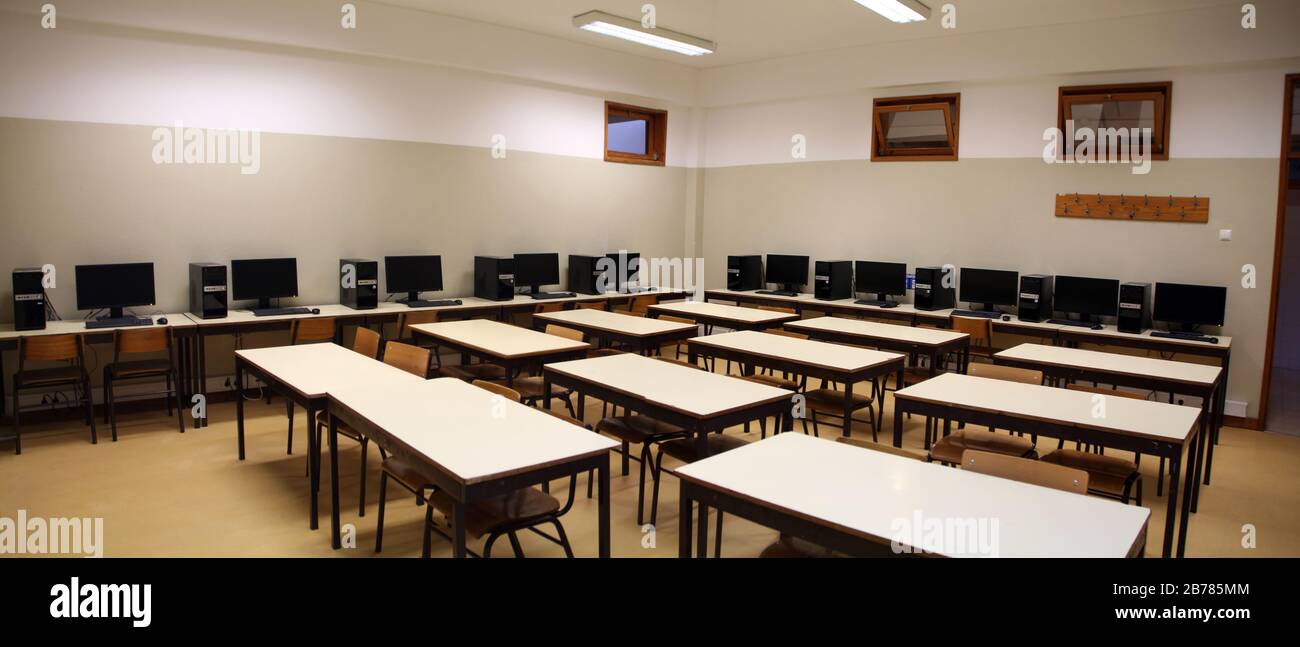View of the interior of a classroom with row of computers on middle ...