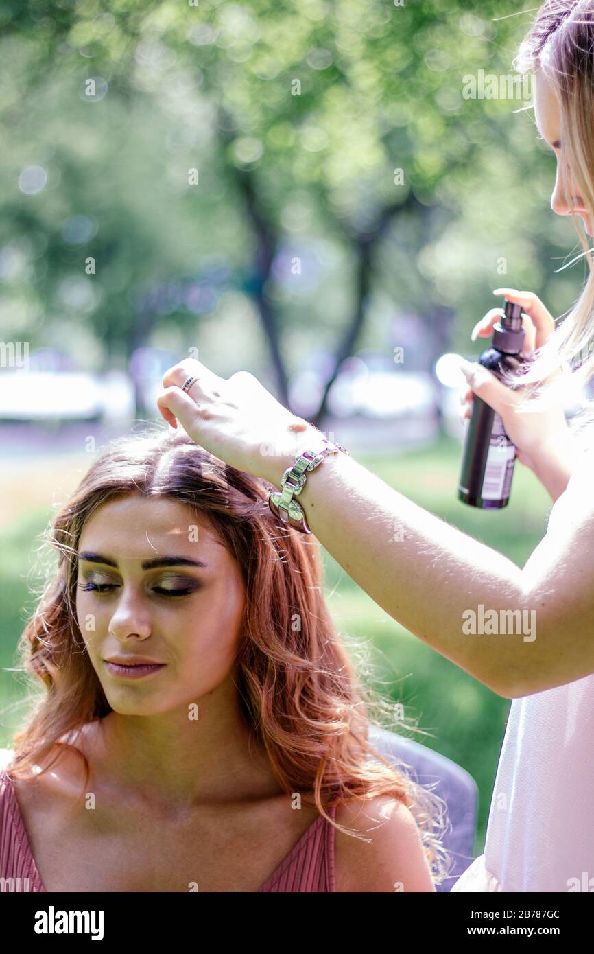 Stylist spraying hairs of young girl with hair spray Stock Photo - Alamy