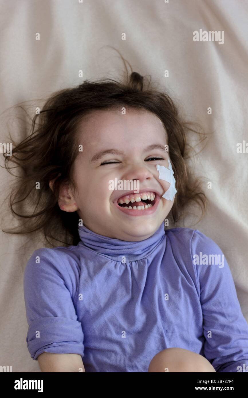 Little kid girl after accident with adhesive band on face laughing ...