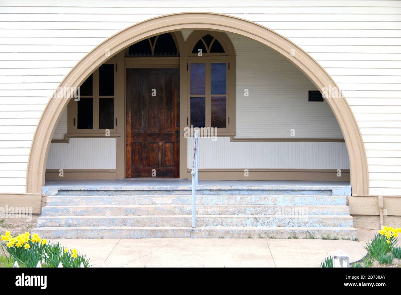 a vintage arched entrance with steps and garden featuring a retro wood ...