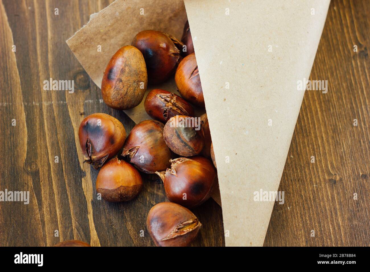 Roasted chestnuts in paper cornet over rustic table Stock Photo - Alamy