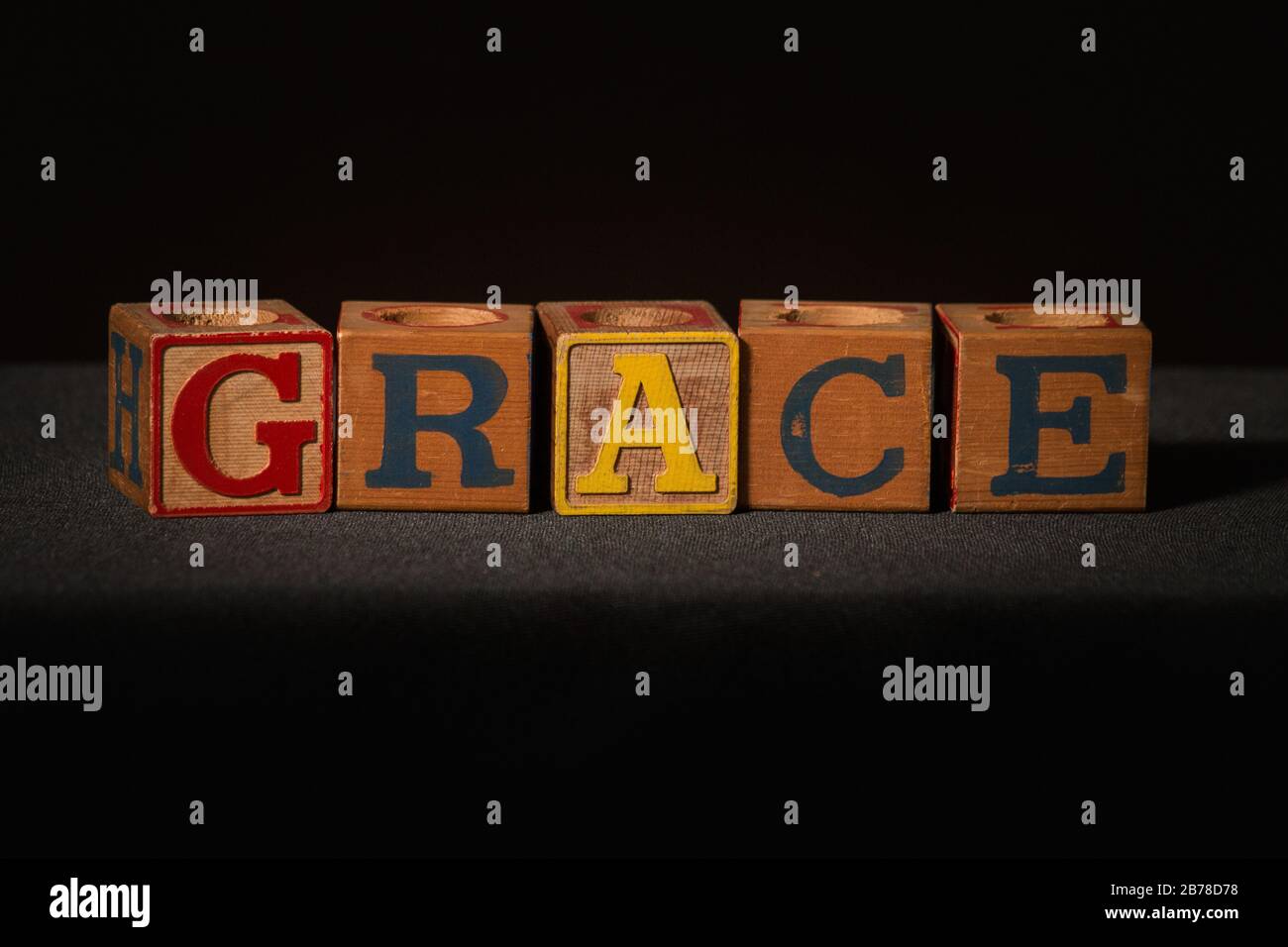 The word grace spelled out in wooden alphabet blocks spotlit against ...