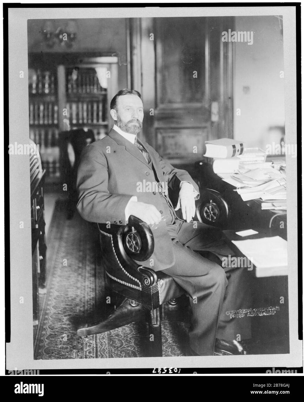 George Sutherland, full-length portrait, seated at desk, facing right ...