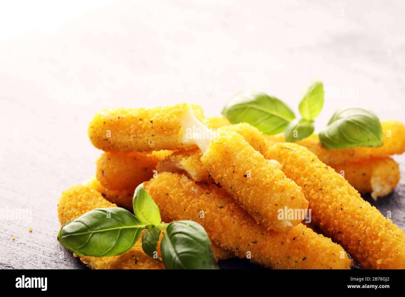 Breaded mozzarella cheese sticks with basil on table Stock Photo - Alamy