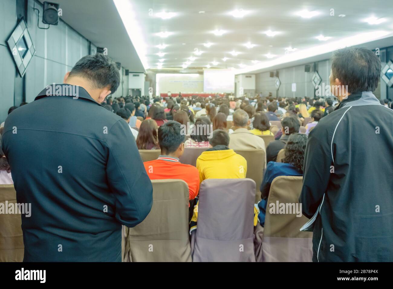 Backside view of spectators standing in a gathering in the back of ...