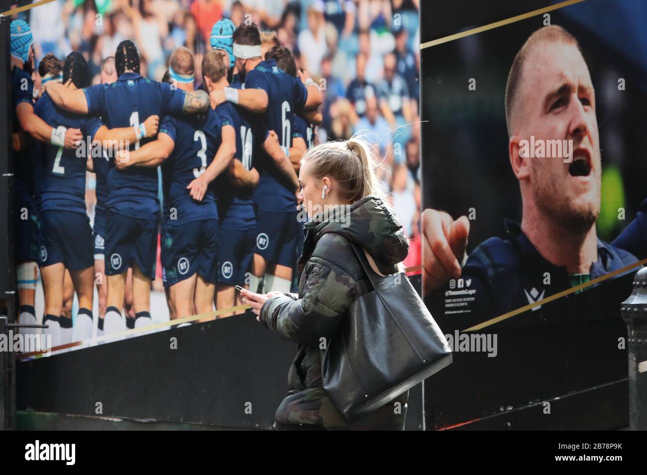 A woman walks past a billboard showing the Scottish Rugby team in ...