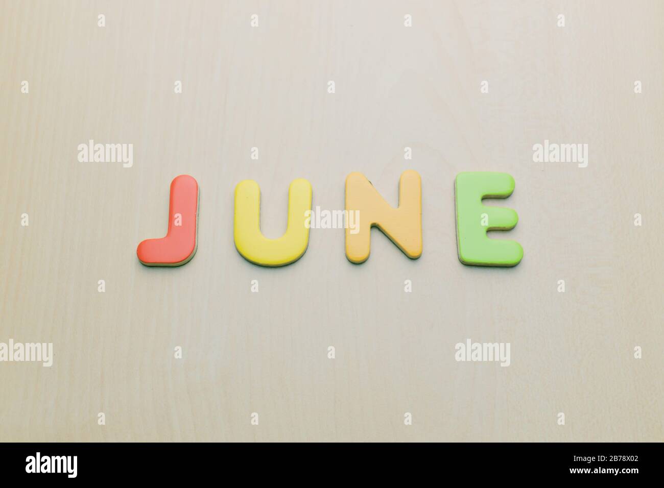 June word written with colorful letters on wooden background, top view ...