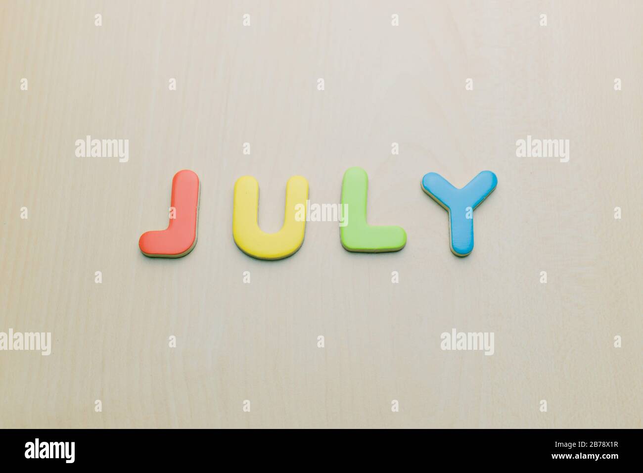July word written with colorful letters on wooden background, top view ...
