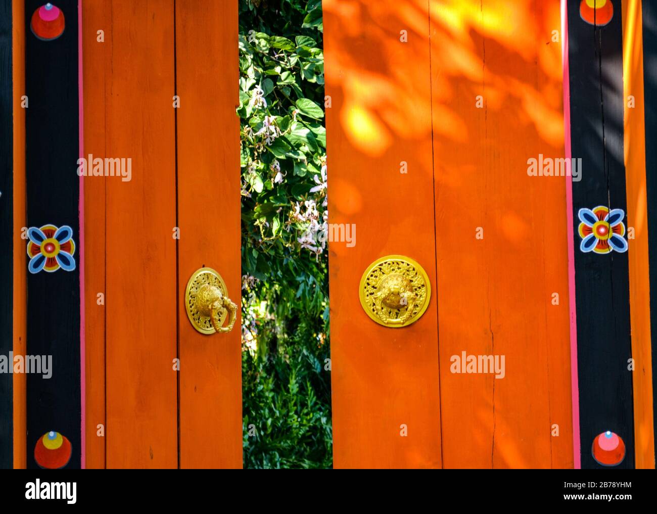 Bhutanese-style orange wooden door with golden door knocker in ...