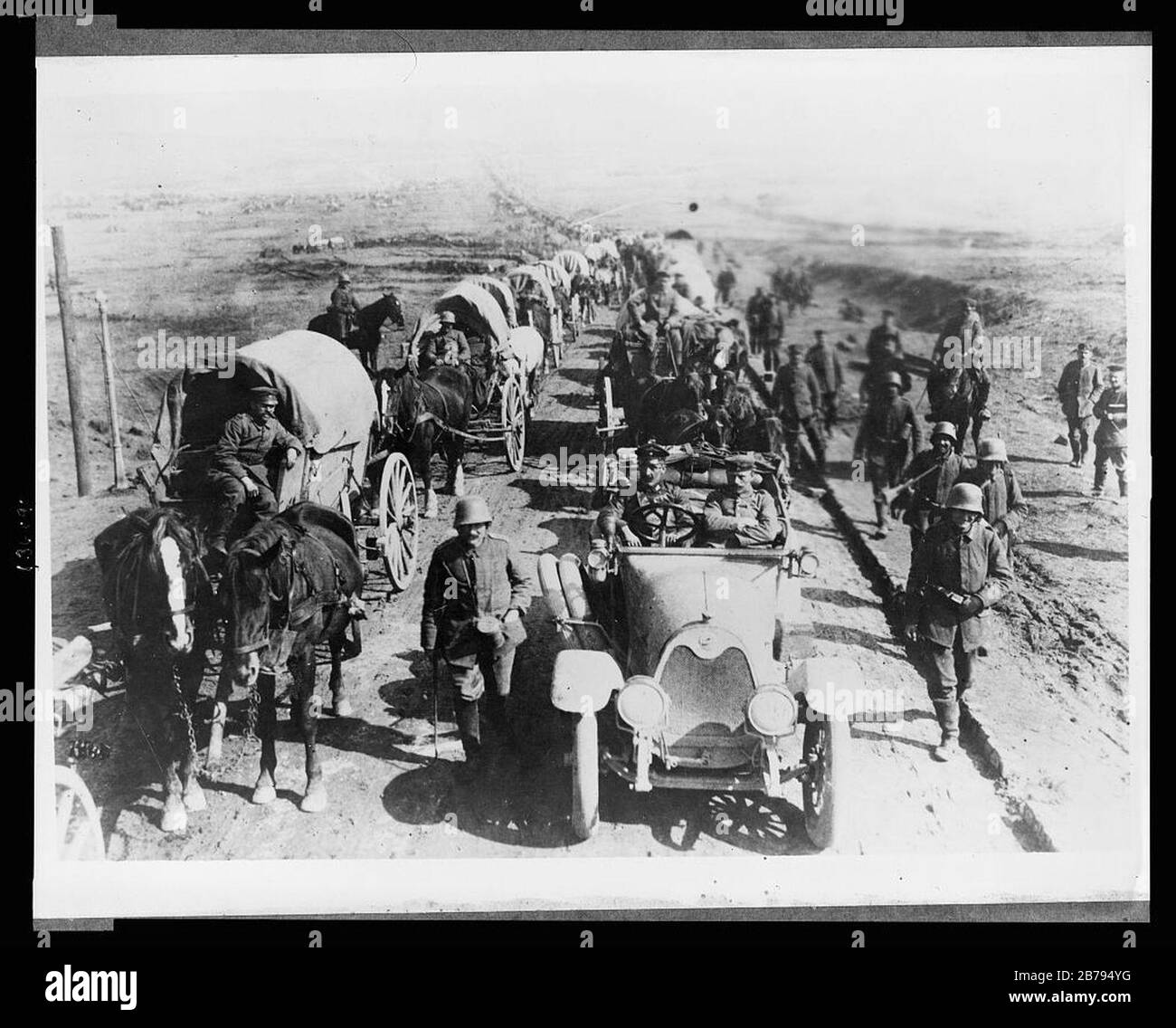 German officers in an automobile on the road with a convoy of wagons ...