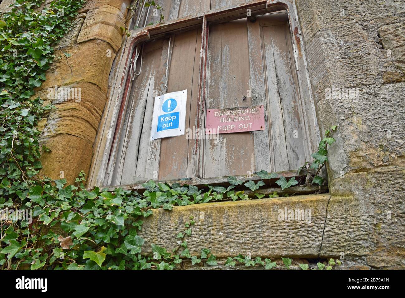 Keep out dangerous buildings sign attached to wooden boarded up window ...