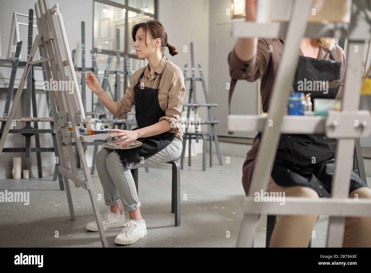 Young students of professional painting course with color palettes and ...