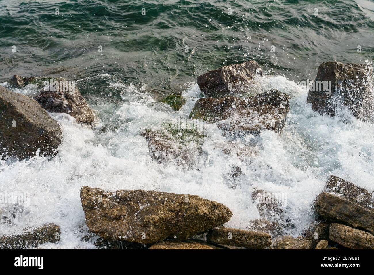 Sea waves hitting the rocks with water splashing around Stock Photo - Alamy