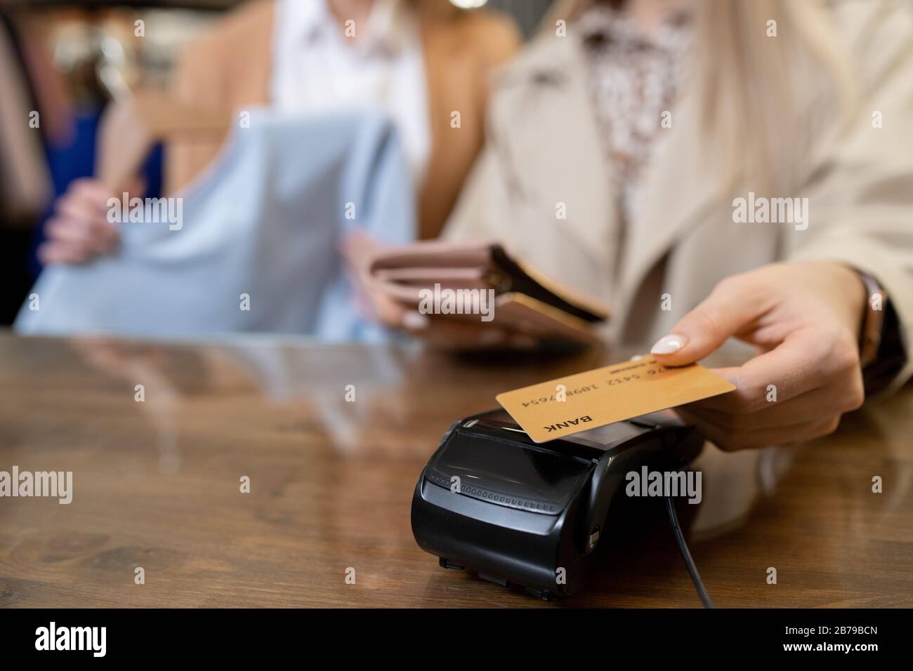 Hand of young female shopper holding plastic card over payment machine ...