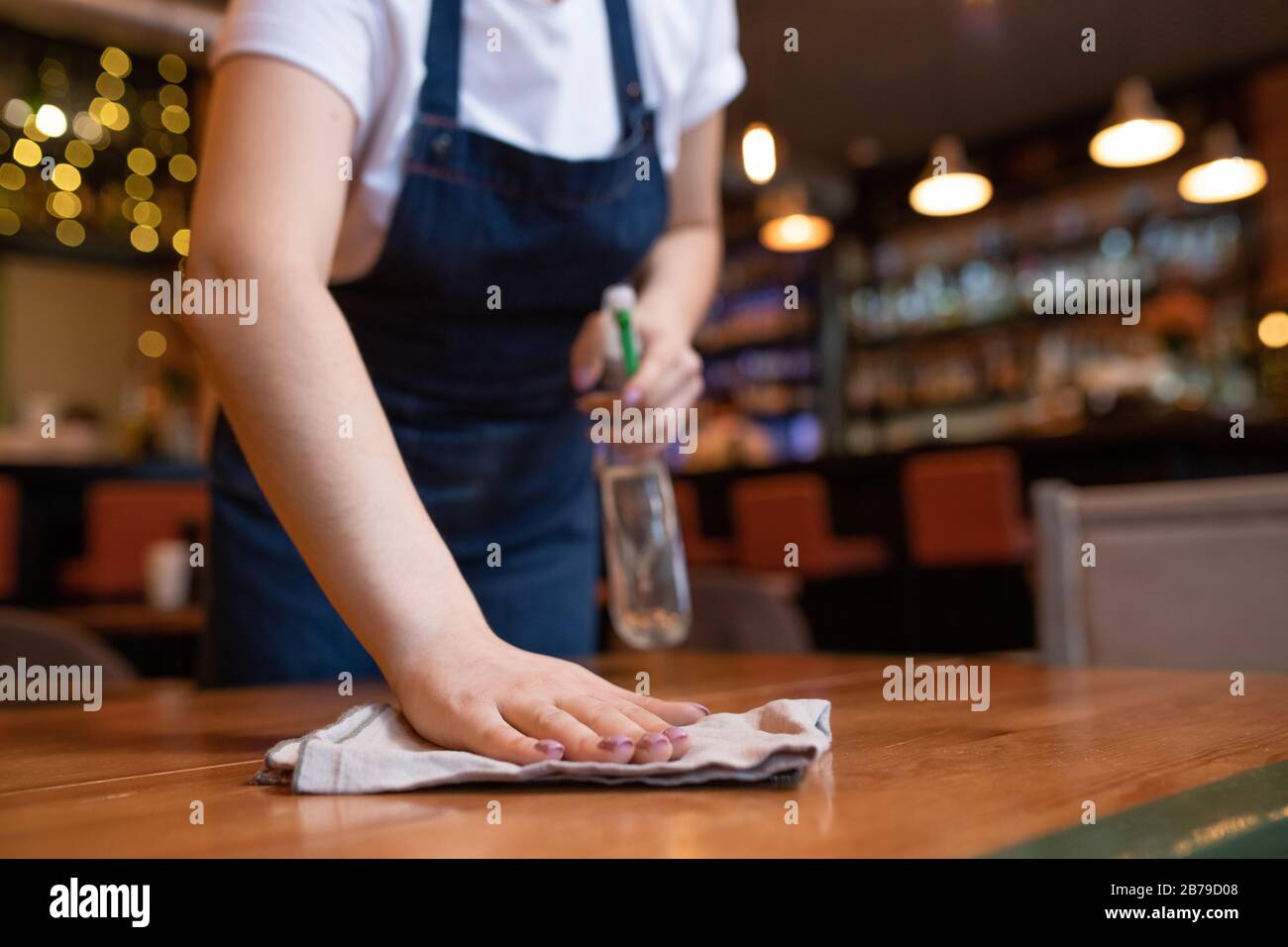 Hand of young contemporary waitress wiping wooden table with duster and ...