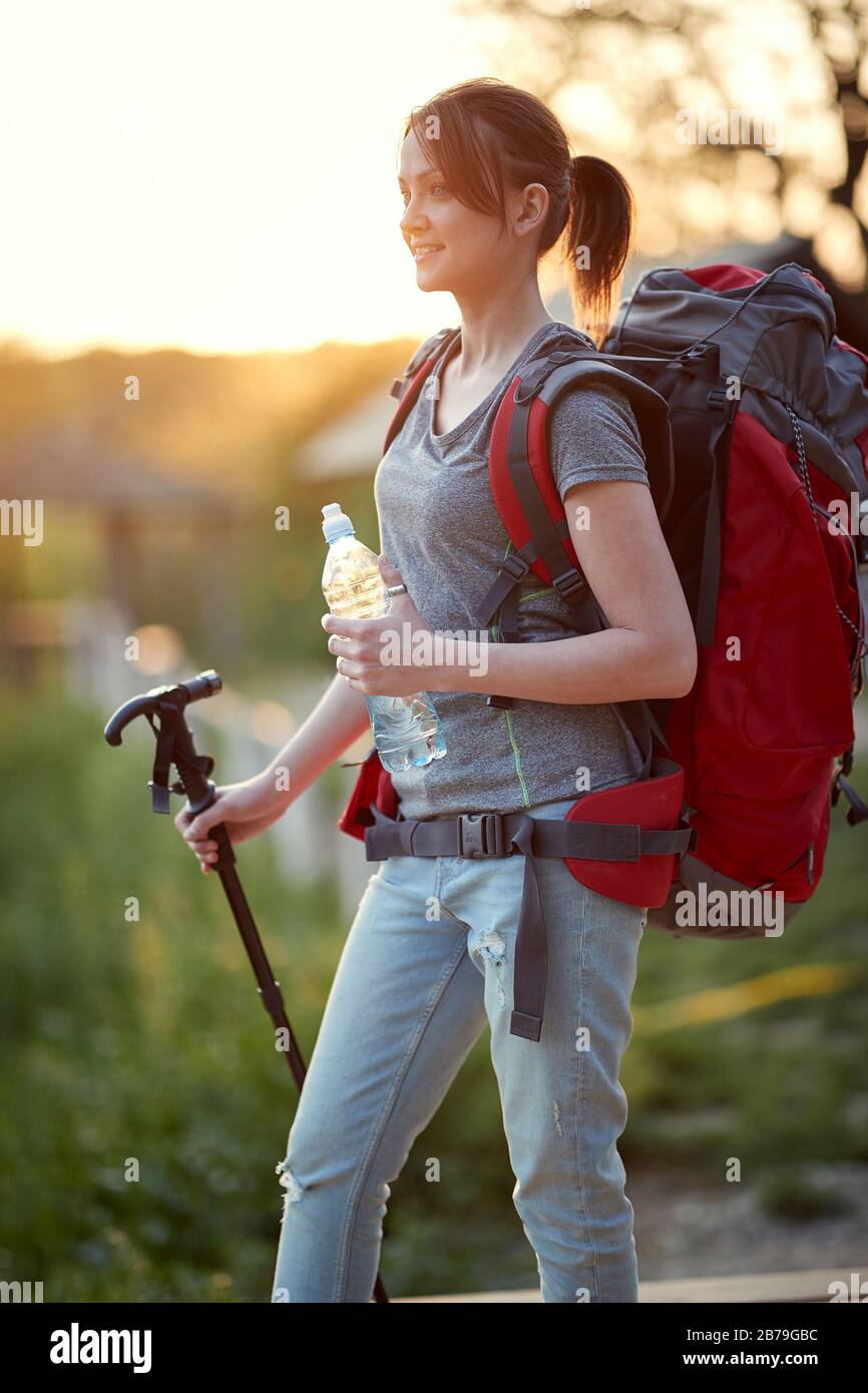 satisfied female backpacker finishing her hiking at sunset in nature ...