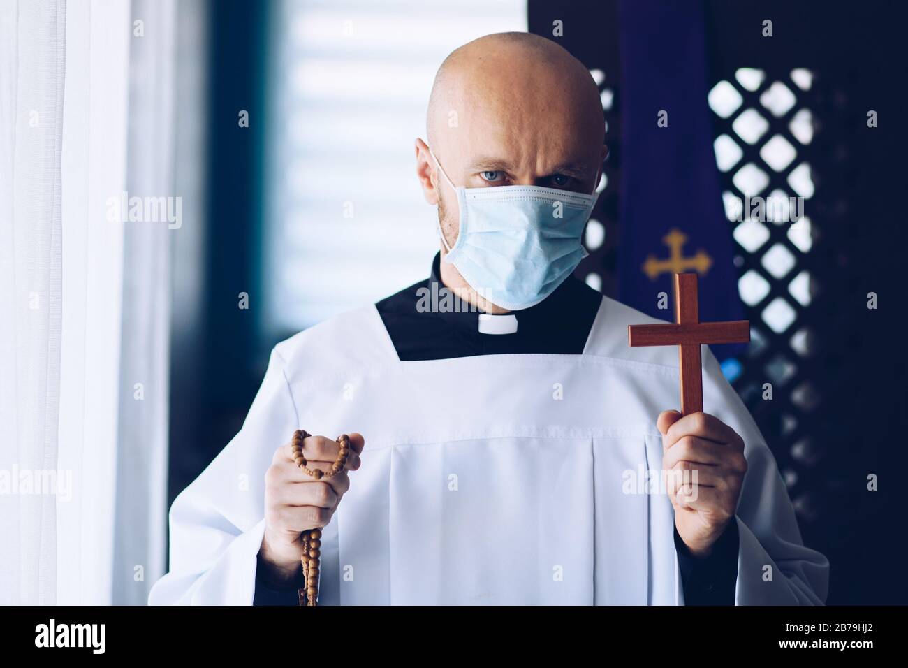 Man priest in medical mask praying with cross and rosary Stock Photo ...