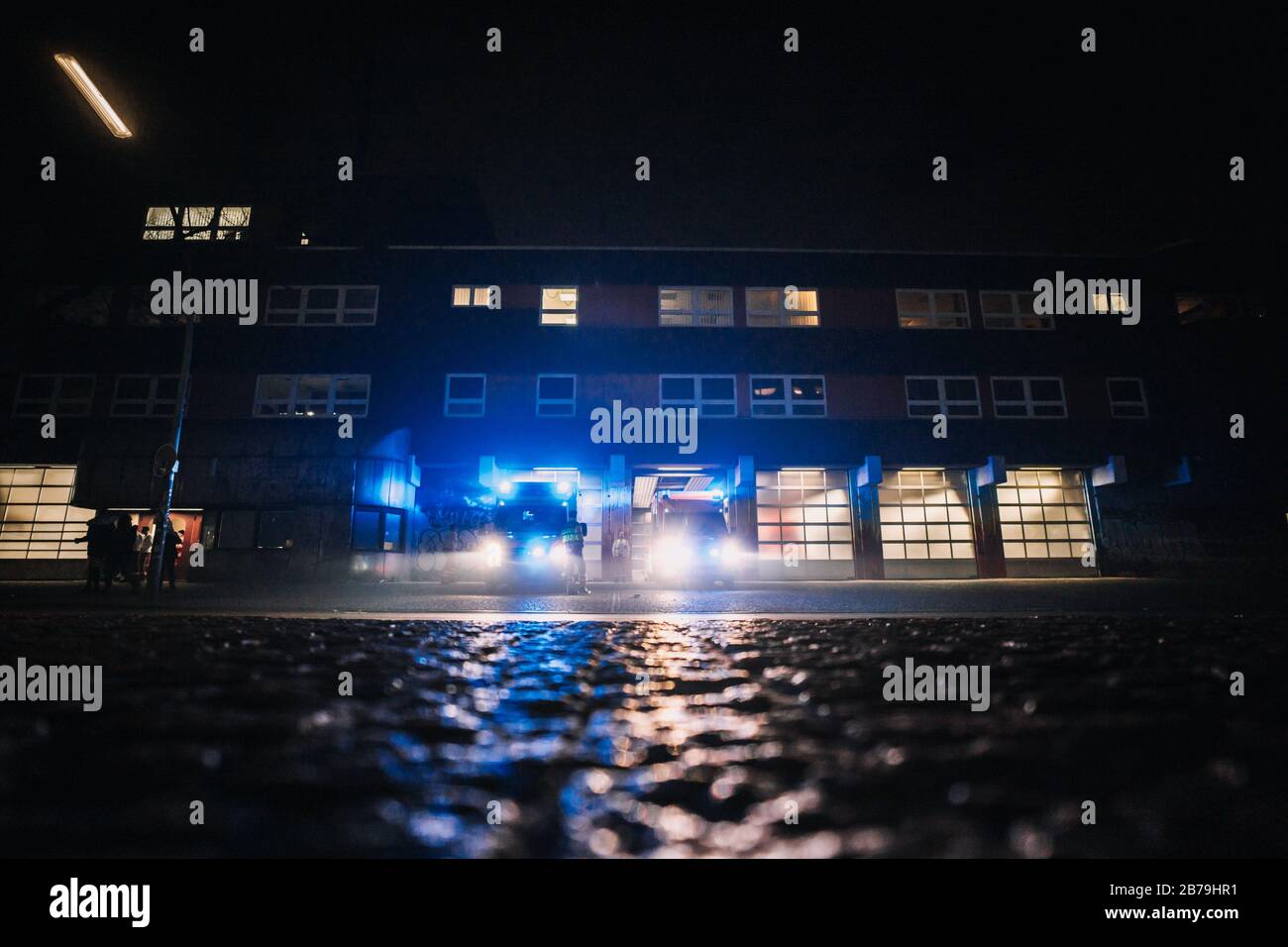 Fire station at night with fire trucks responding to emergency call and ...