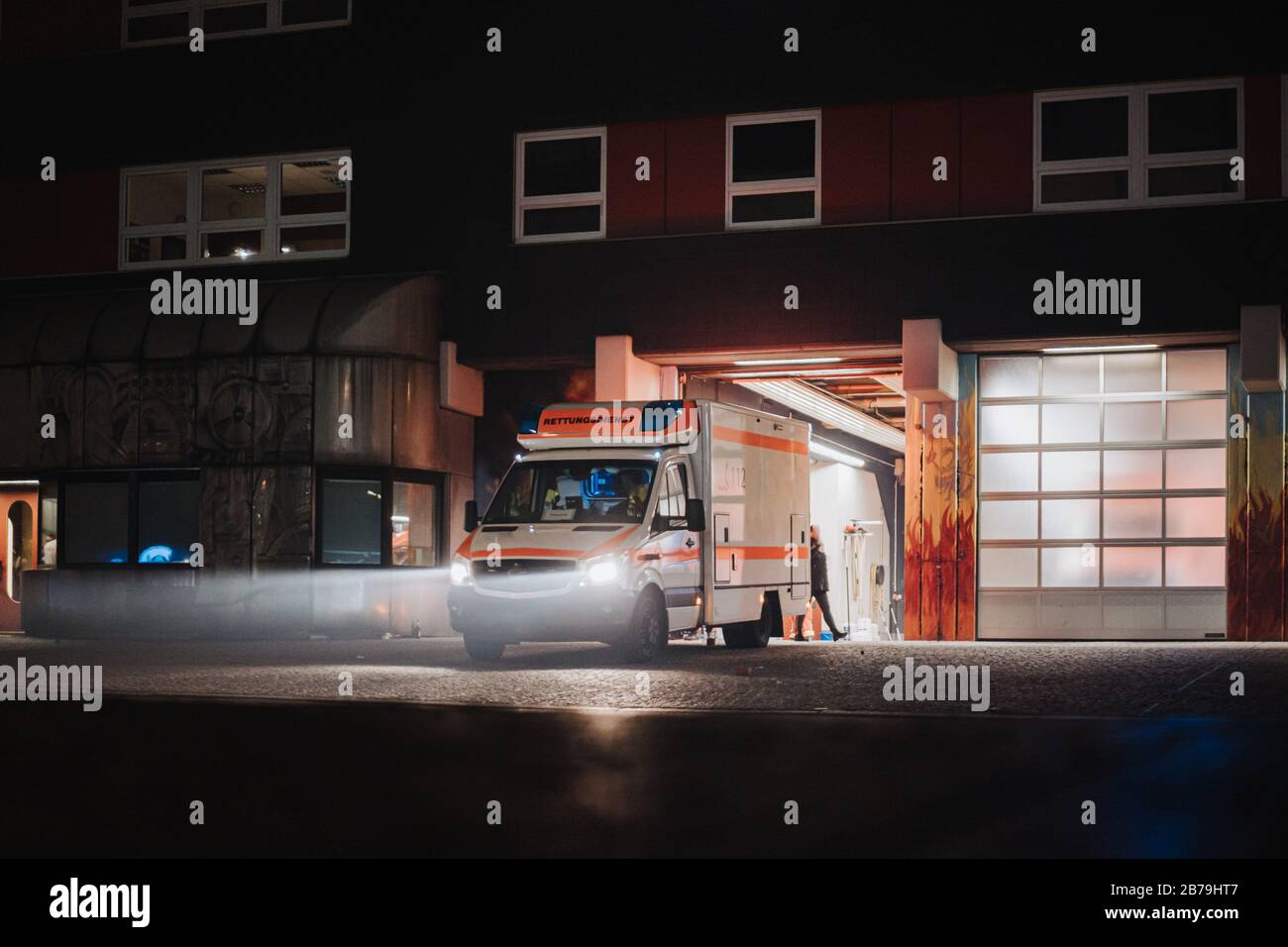 Fire station at night with fire trucks responding to emergency call and ...