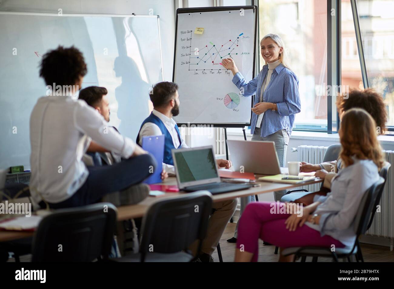 Smiling woman demonstrating presentation on board while talking with ...