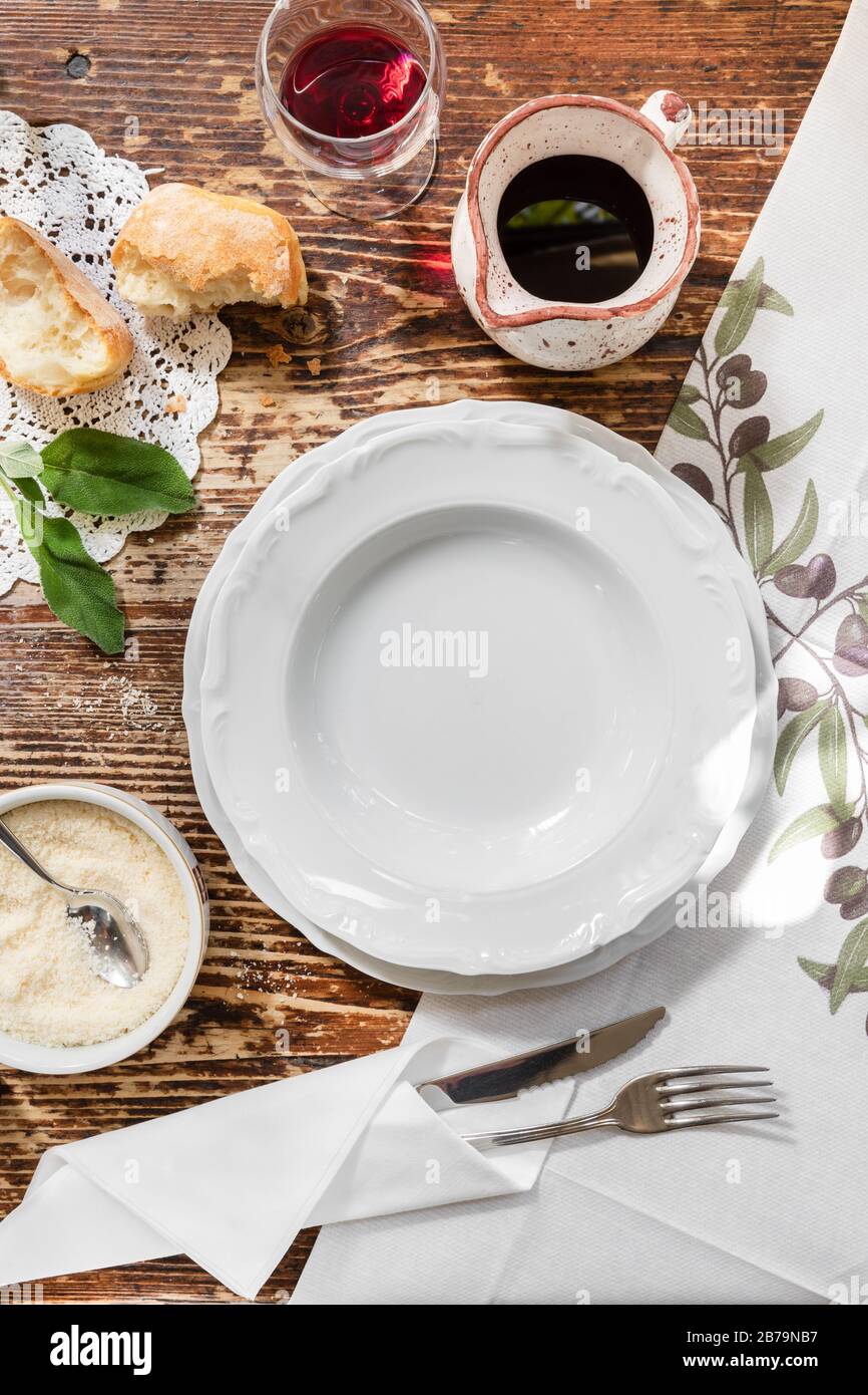Traditional Italian table set with plate, cutlery, rustic bread, wine ...